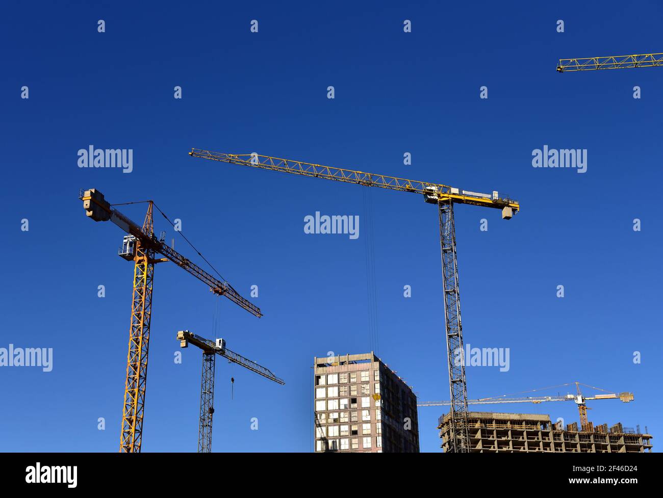 Grues à tour travaillant sur le chantier contre ciel bleu. Grue de ...