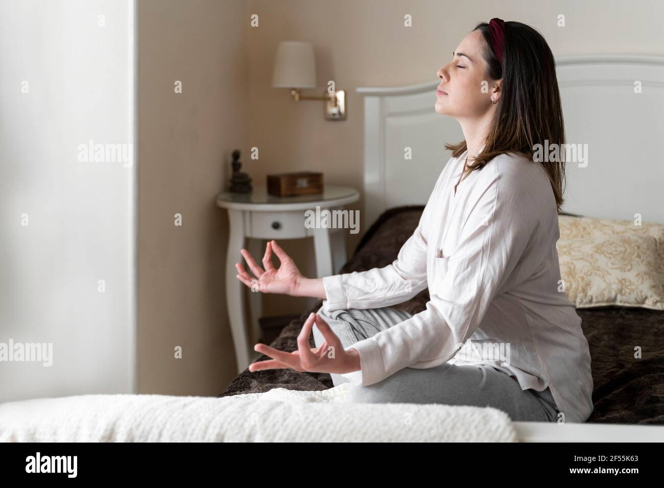 Jeune Femme Assise En Tailleur Sur Le Lit Banque De Photographies Et D