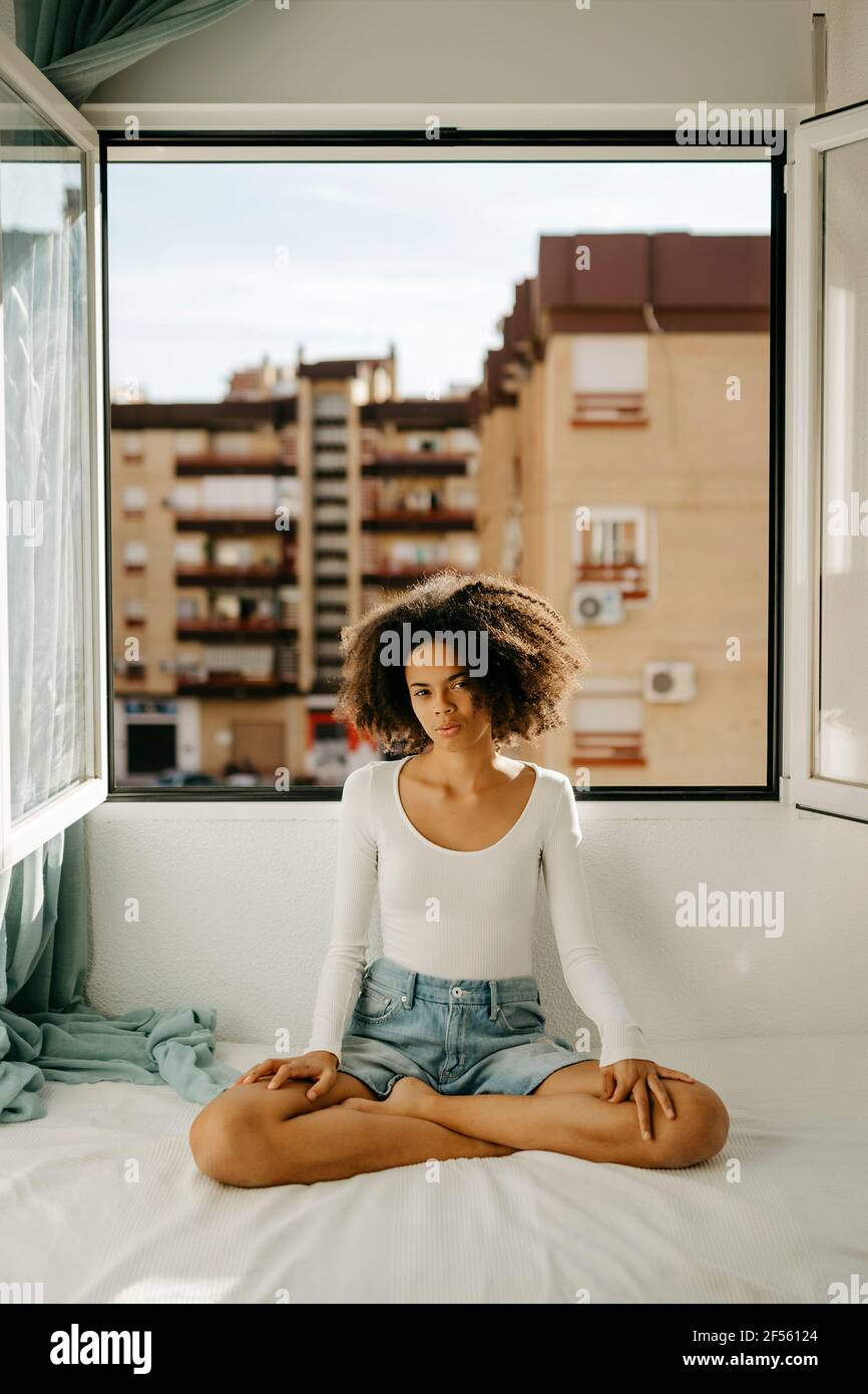 Jeune Femme Assise En Tailleur Sur Le Lit Banque De Photographies Et D