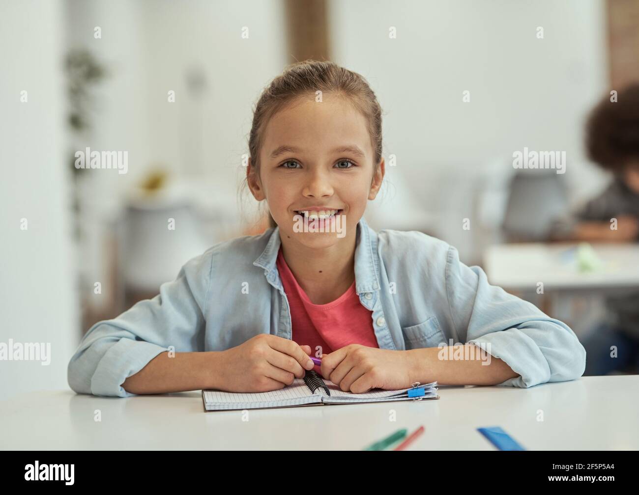 Joli élève. Magnifique petite fille d'école souriant à l'appareil photo ...