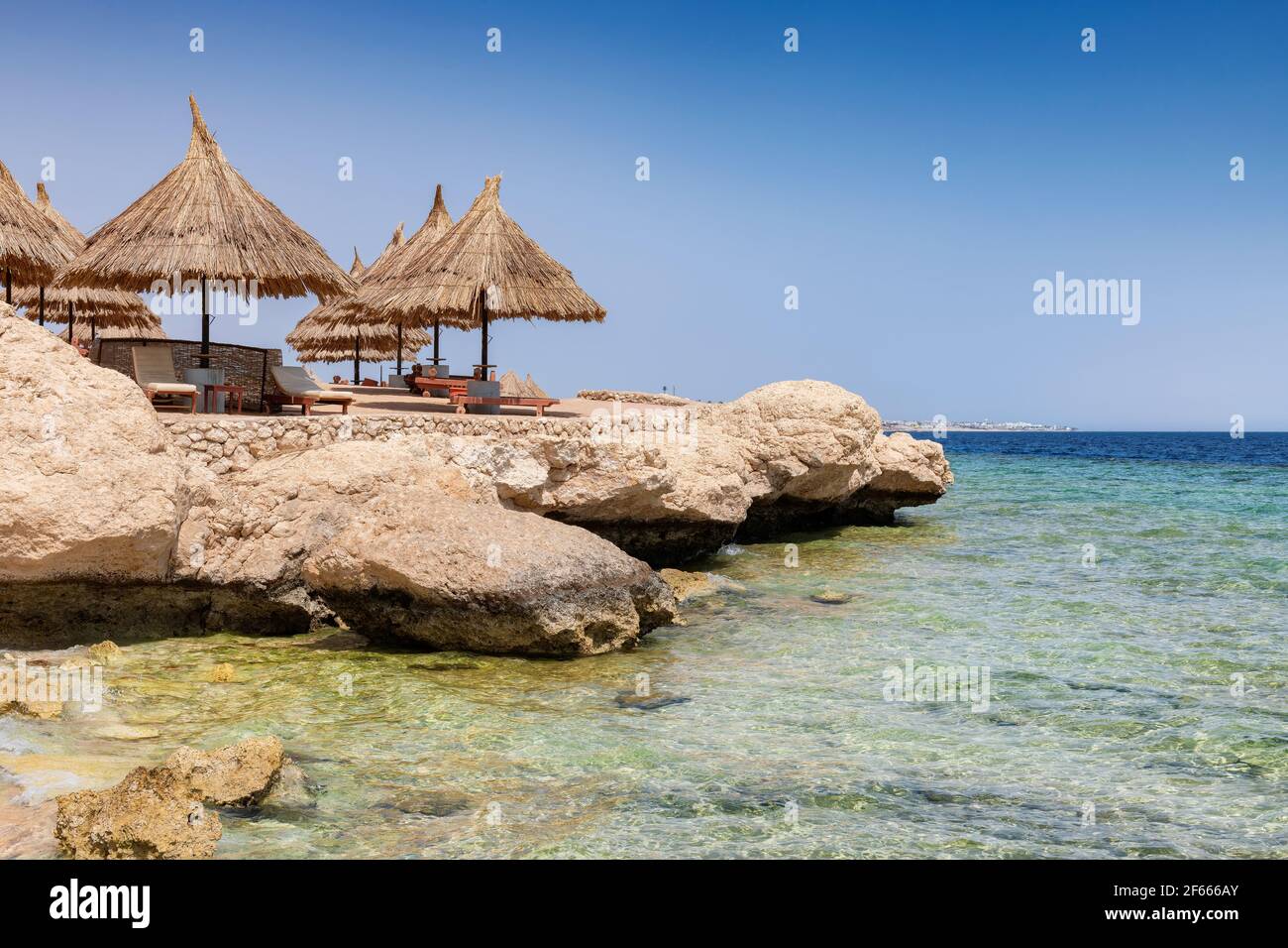 Plage tropicale ensoleillée avec parasols dans la plage de corail de la ...