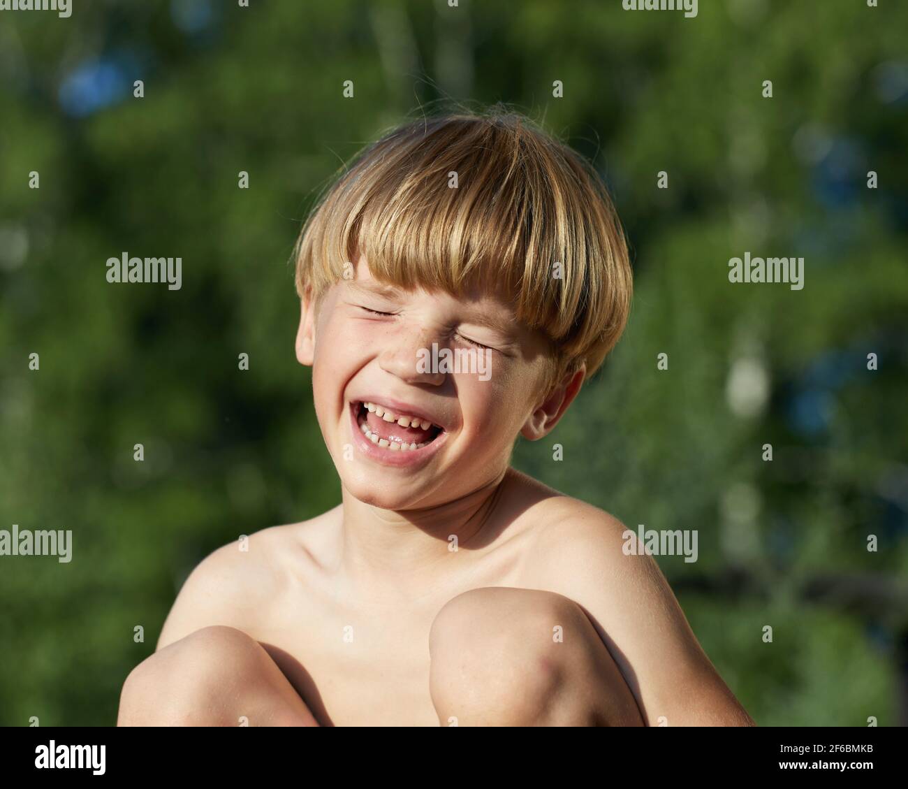 Portrait d'un petit garçon nu qui s'accrouplisse sur des haunches avec ...
