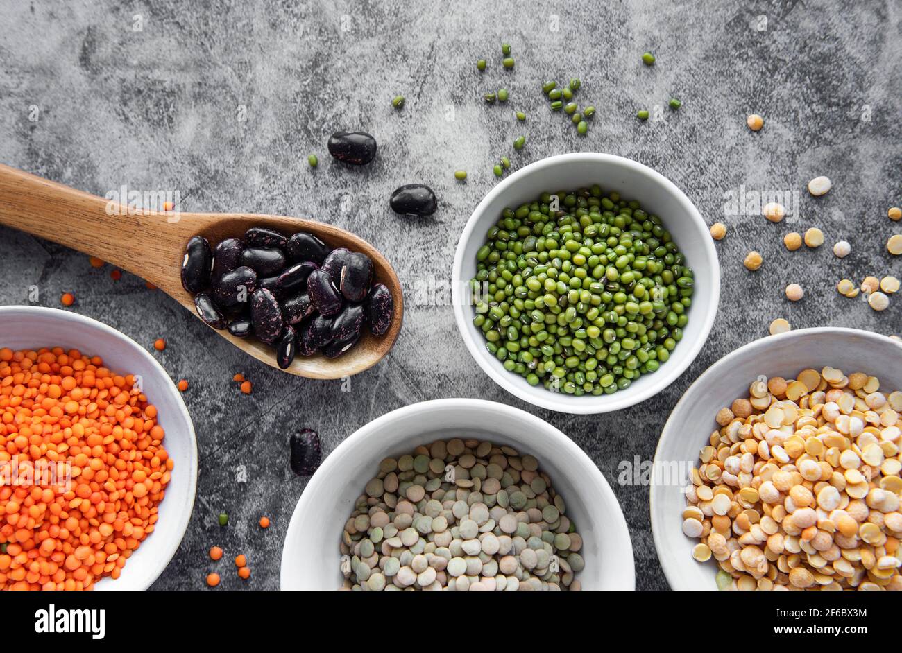 Bols avec différents types de légumineuses sur un béton gris arrière ...