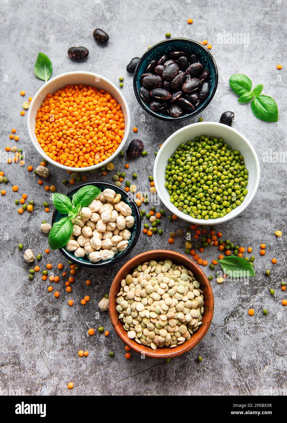 Bols avec différents types de légumineuses sur un béton gris arrière ...