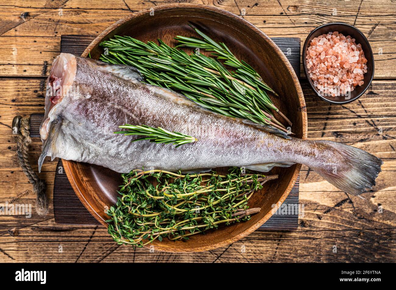 Morue crue ou poisson-morue dans une assiette en bois avec des herbes ...