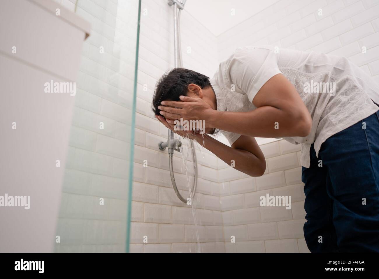 Le jeune musulman exécute l'ablution wudhu avant la prière à la maison ...