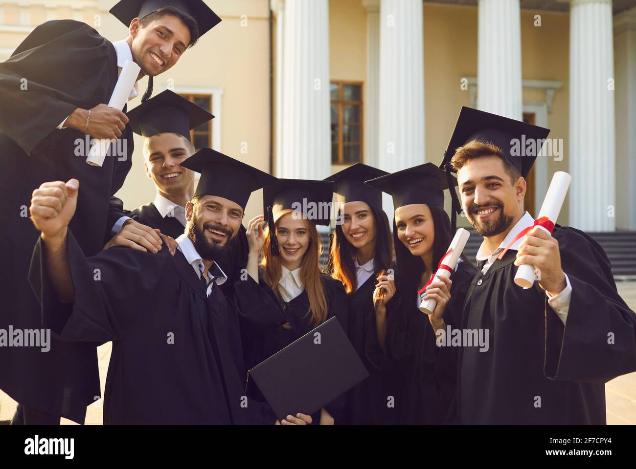 Groupe de diplômés en robes noires avec diplômes en mains après la ...