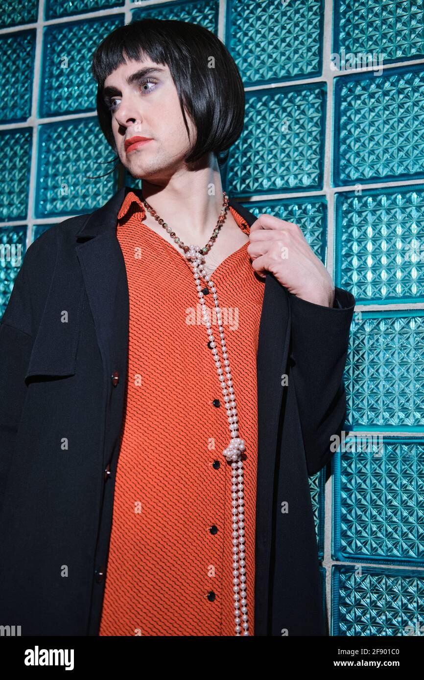 Beau transgenre posant dans la robe et le collier de femme contre le ...