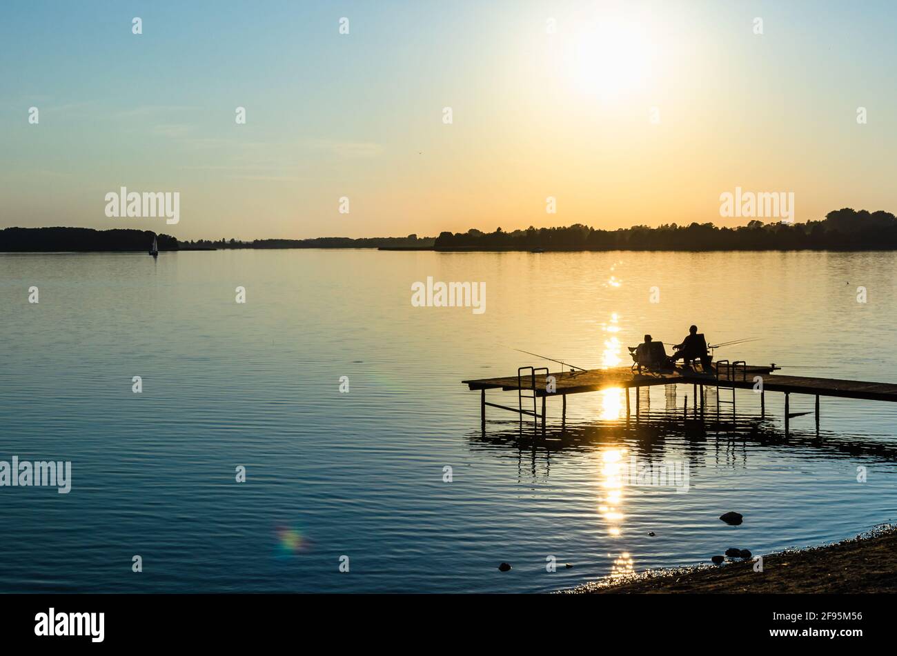Les pêcheurs à la ligne sur la jetée pêchent du poisson. Lac Święcajty ...