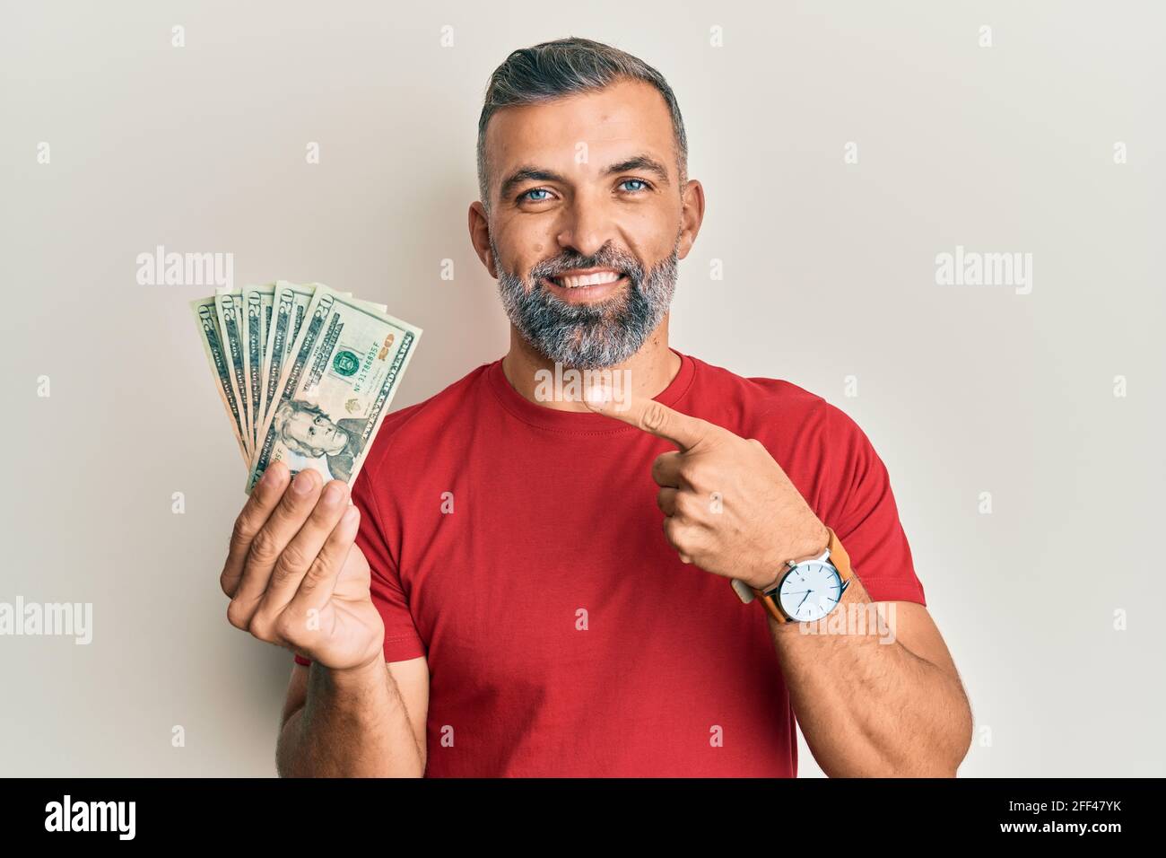Homme beau d'âge tenant 20 billets de dollars souriant heureux pointer ...
