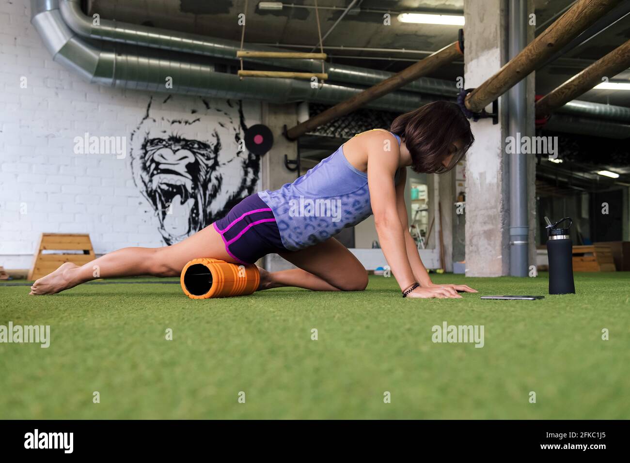 sportswoman dans la salle de gym étirant et massant ses muscles avec un ...