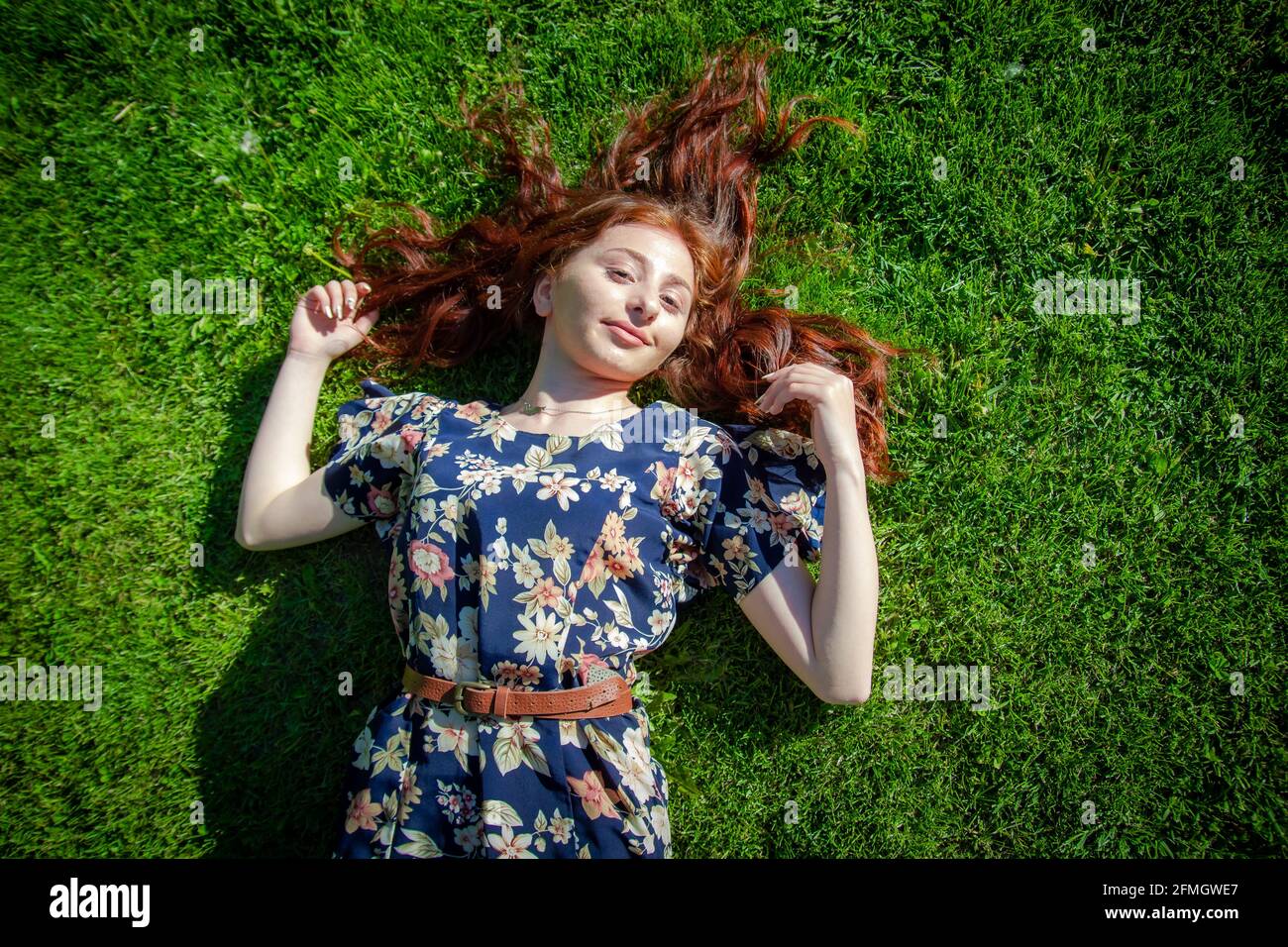 une femme aux cheveux rouges dans le parc, une jolie femme dans l'herbe ...