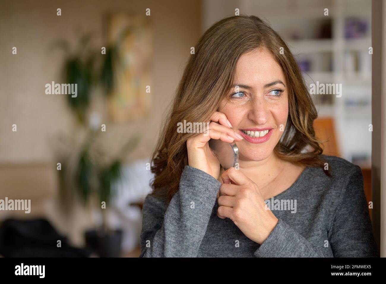 Une femme d'âge moyen bavarde avec le sourire sur son téléphone mobile ...
