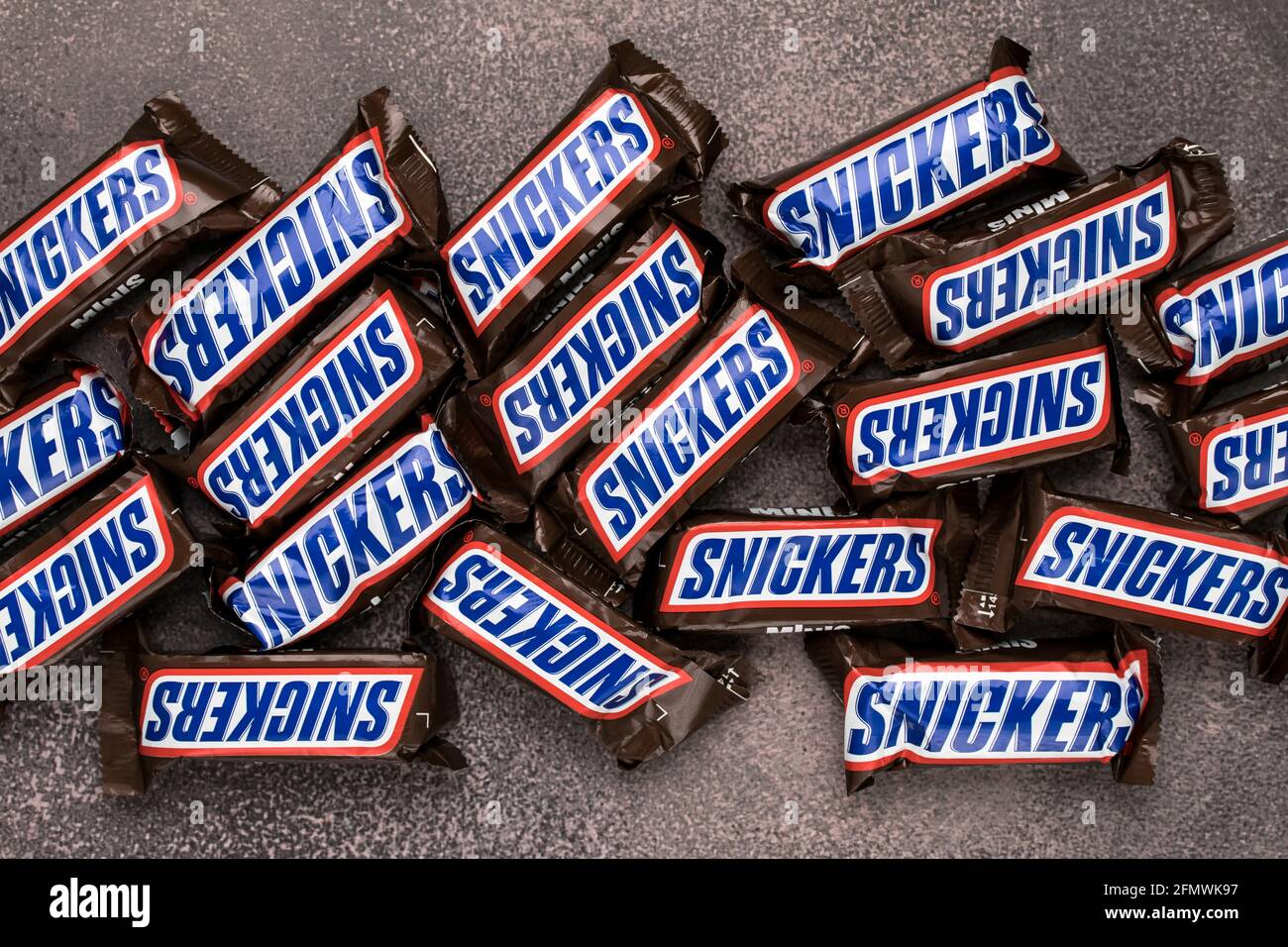 Un tas de barres de chocolat Snickers enveloppées sur fond marron foncé ...