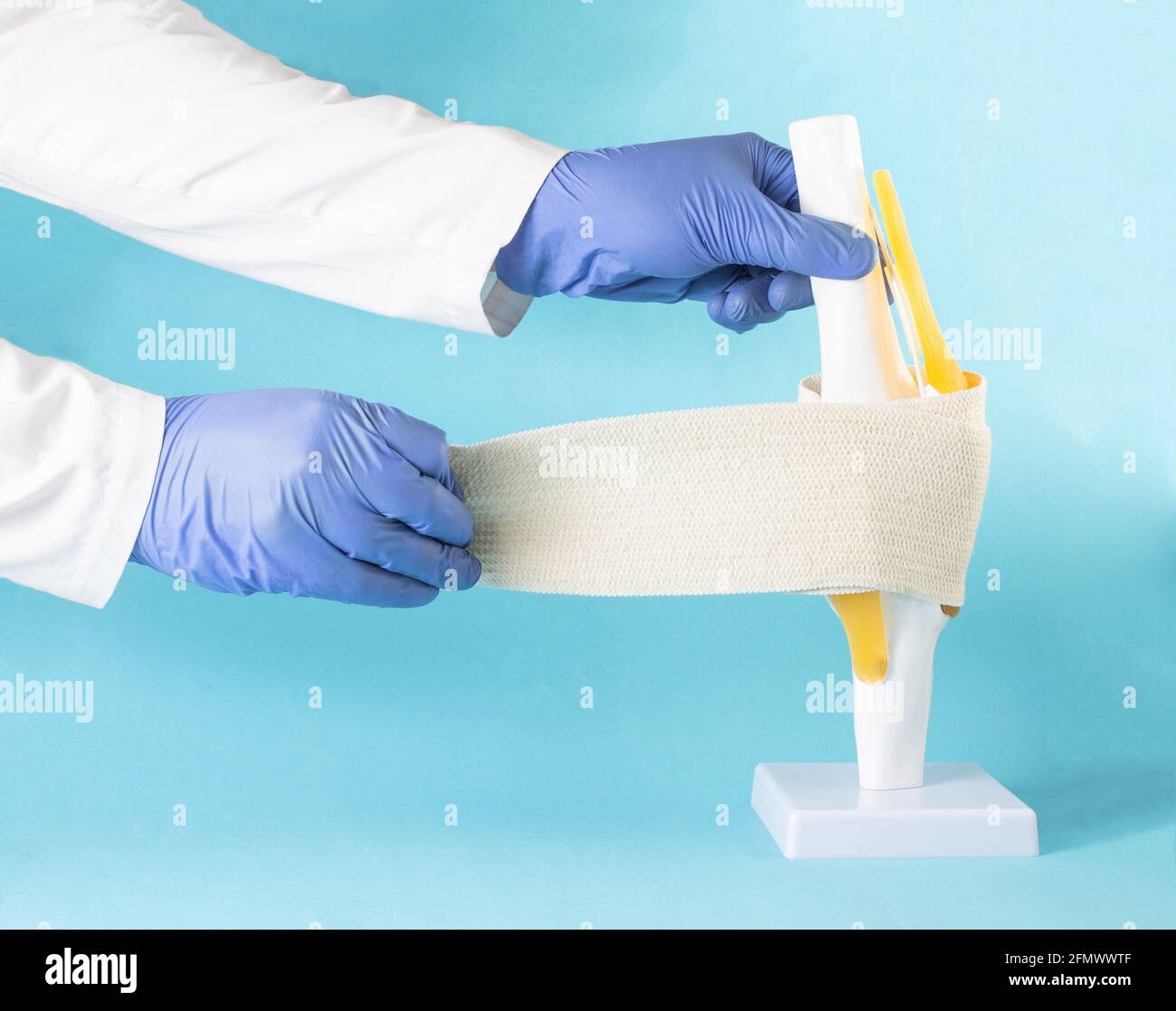 Le médecin enroule un bandage élastique sur une articulation du genou ...