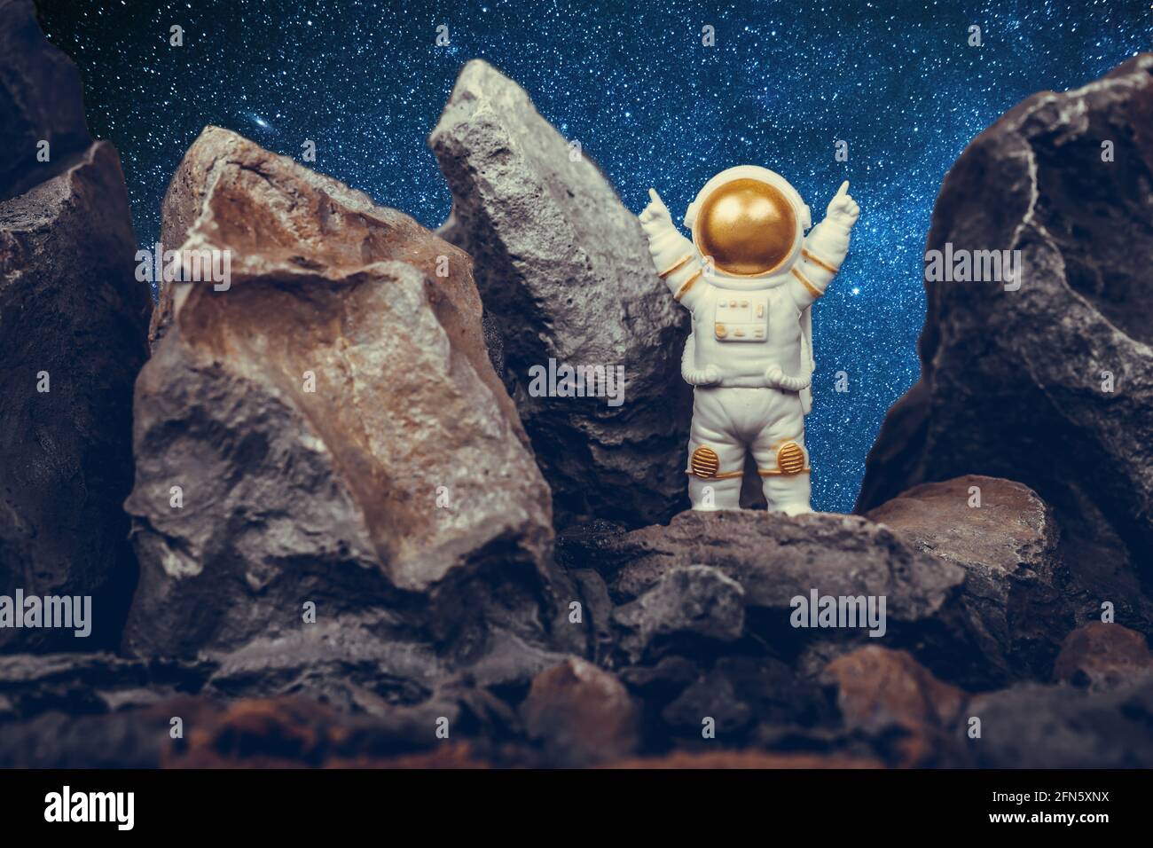 Astronaute satisfait levant les bras sur une montagne rocheuse ...