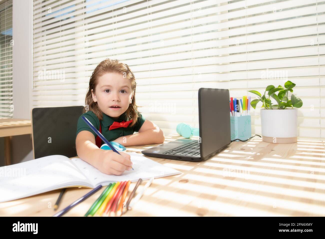 Un adorable élève écrit au carnet de notes en classe à l'école ...