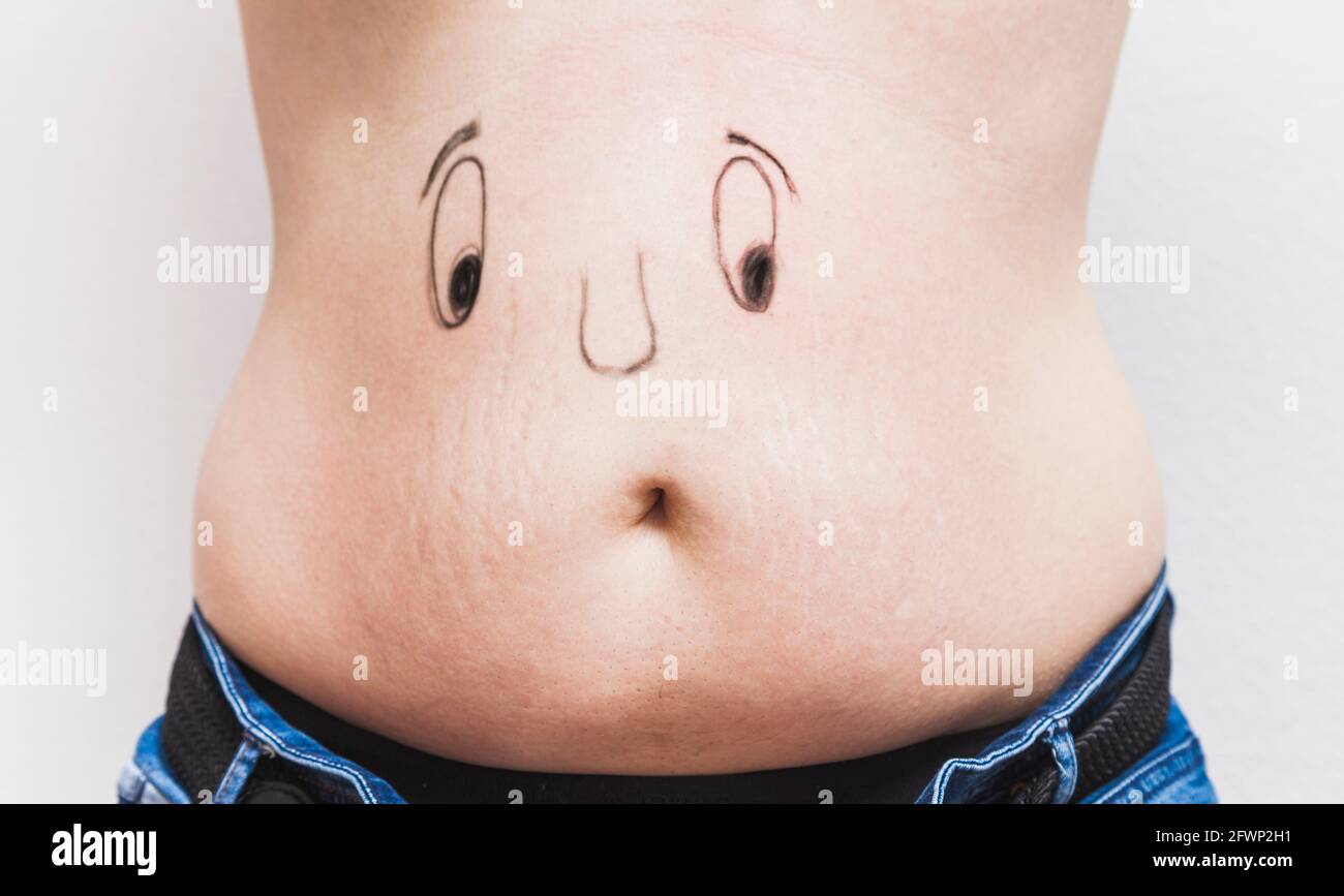 Un visage drôle peint sur le ventre d'un gros homme méconnaissable. Les ...