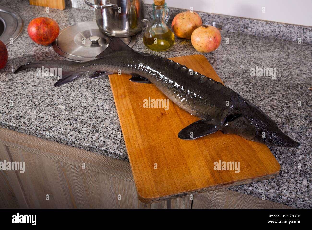 Esturgeon frais entier allongé sur une planche à découper en bois avec ...