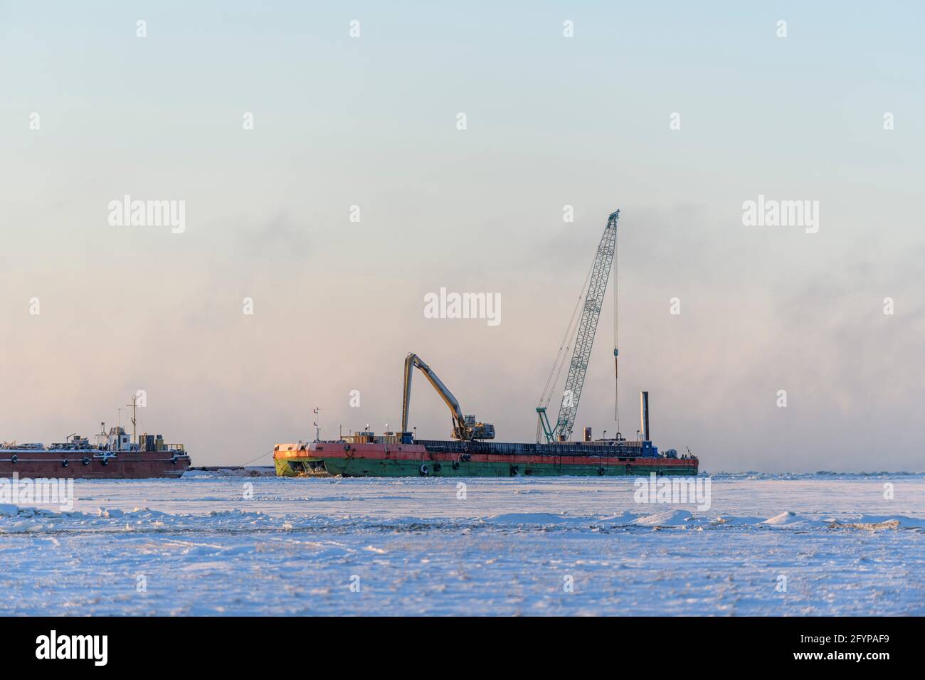 Barge avec grue. Dragueur travaillant en mer. Coucher de soleil dans la ...
