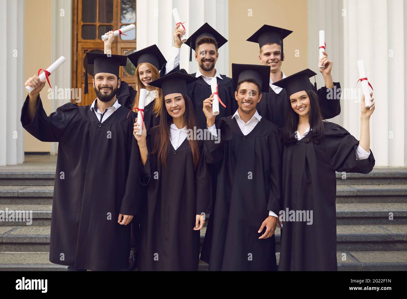Groupe heureux diplômé en robes noires avec des diplômes en mains après ...