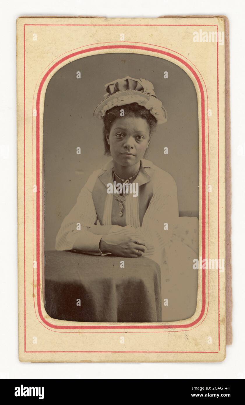 Une femme afro-américaine non identifiée assise à une table. Elle porte ...