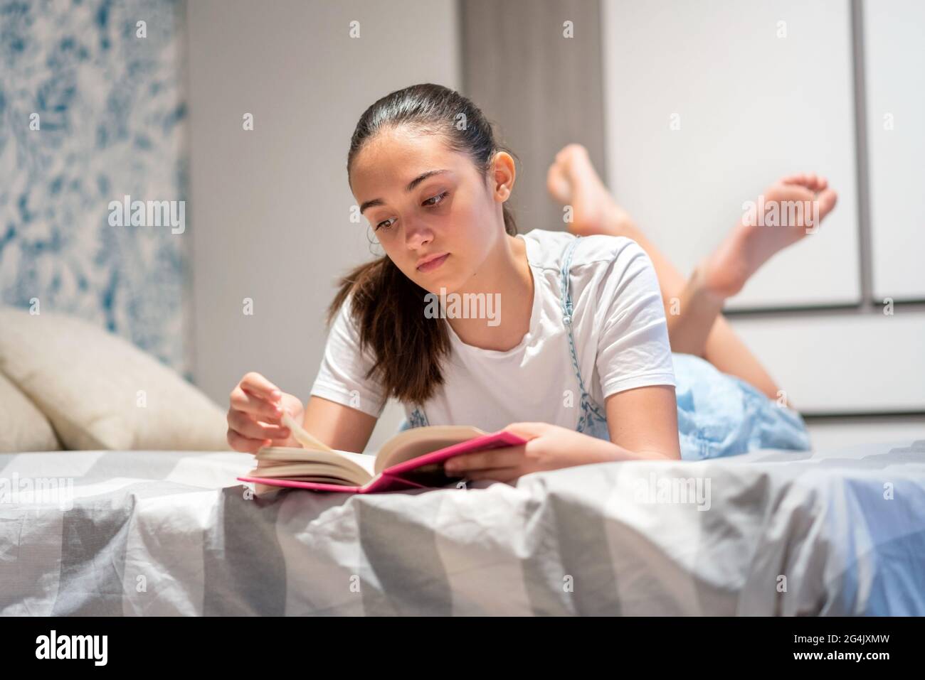 Une Jeune Adolescente Pieds Nus Allongé Sur Son Lit Lisant Un Livre Ou