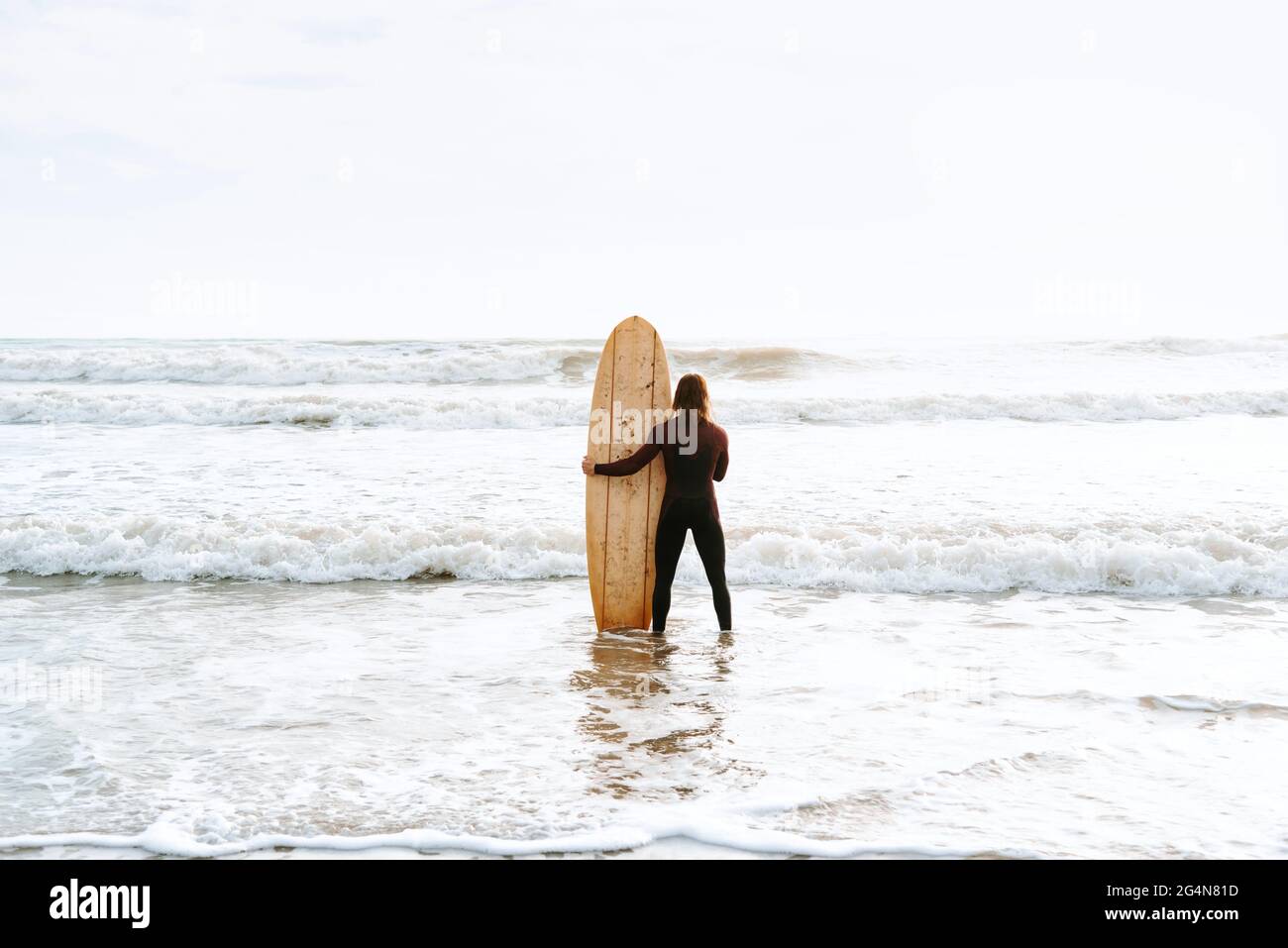 Vue arrière d'un surfeur méconnaissable vêtu d'une combinaison de ...