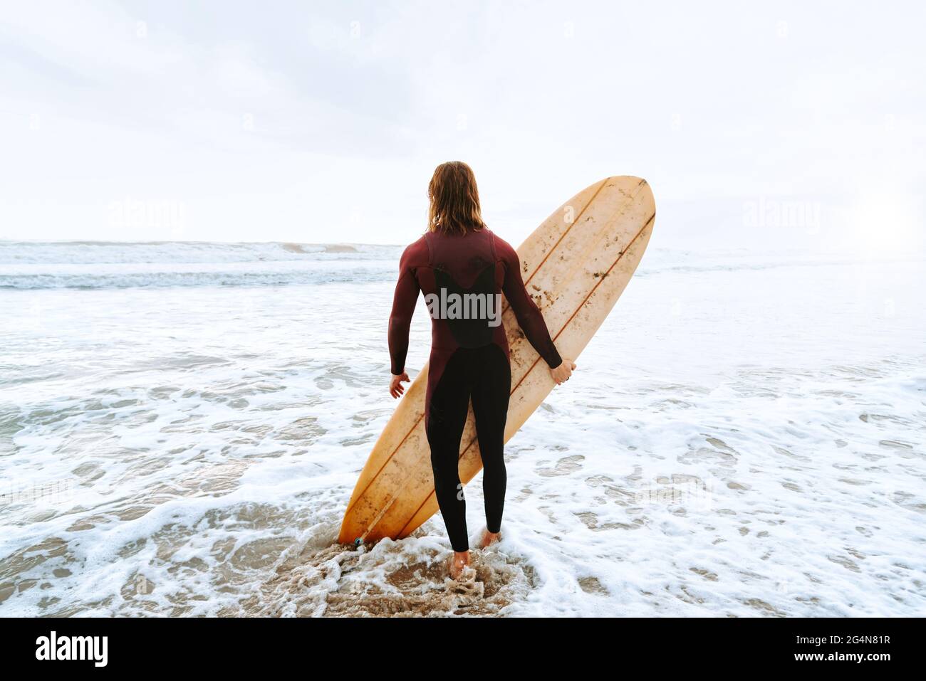 Vue arrière d'un surfeur méconnaissable vêtu d'une combinaison de ...