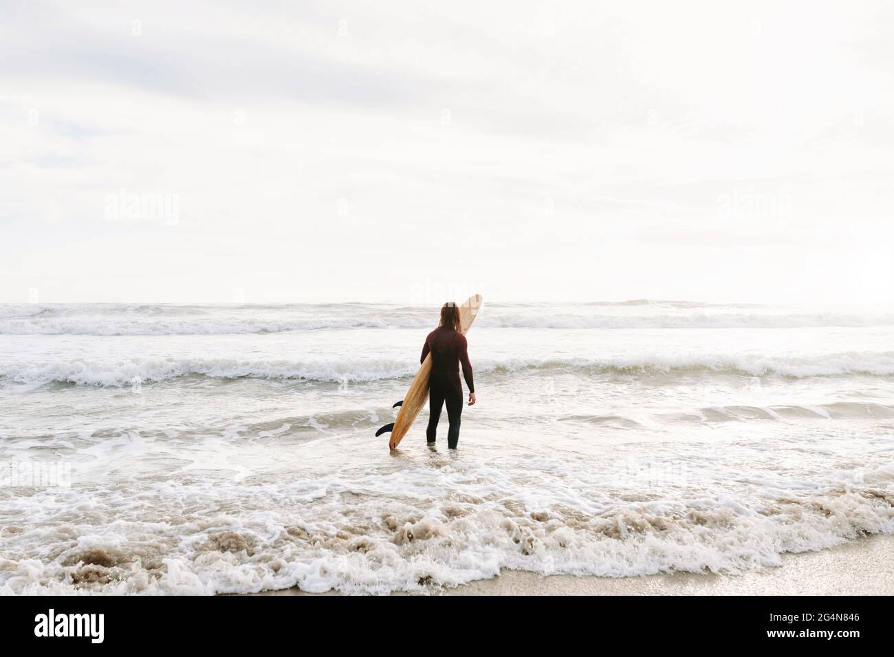 Vue arrière d'un surfeur méconnaissable vêtu d'une combinaison de ...