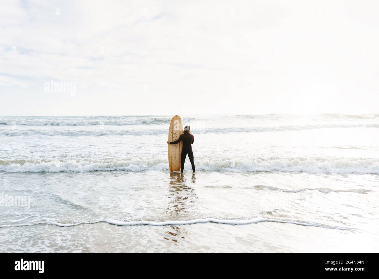Vue arrière d'un surfeur méconnaissable vêtu d'une combinaison de ...