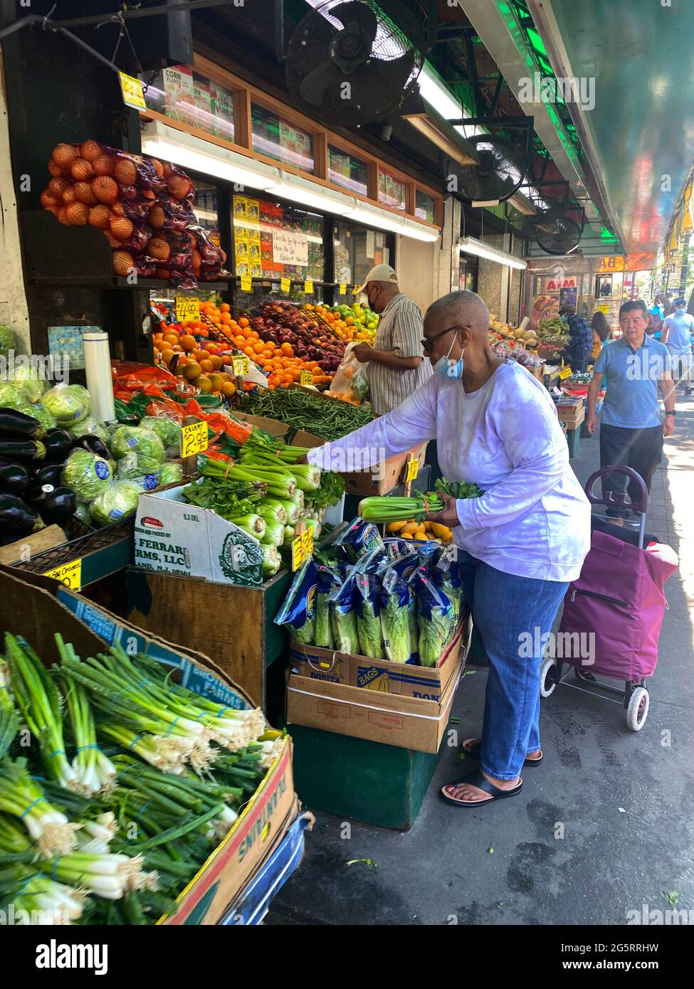 Les gens magasinent pour des fruits et des légumes dans un marché local ...