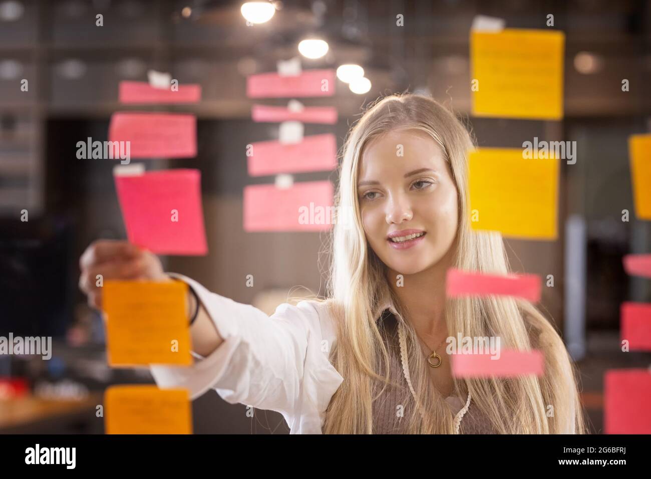 Les jeunes femmes qui adhèrent aux post-its sur un tableau d'idées ...