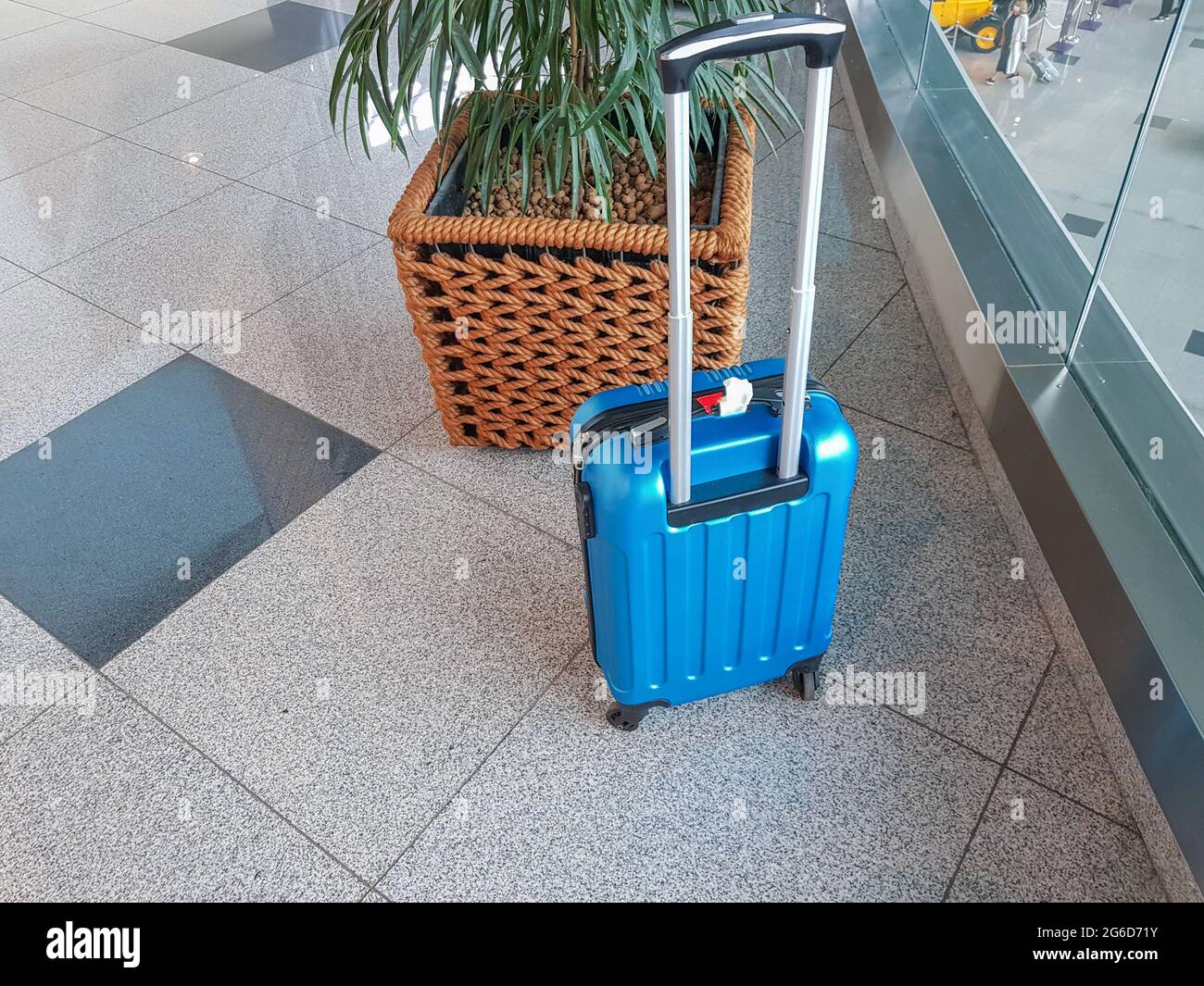 Une valise bleue à roulettes, située sur un sol en marbre dans un ...