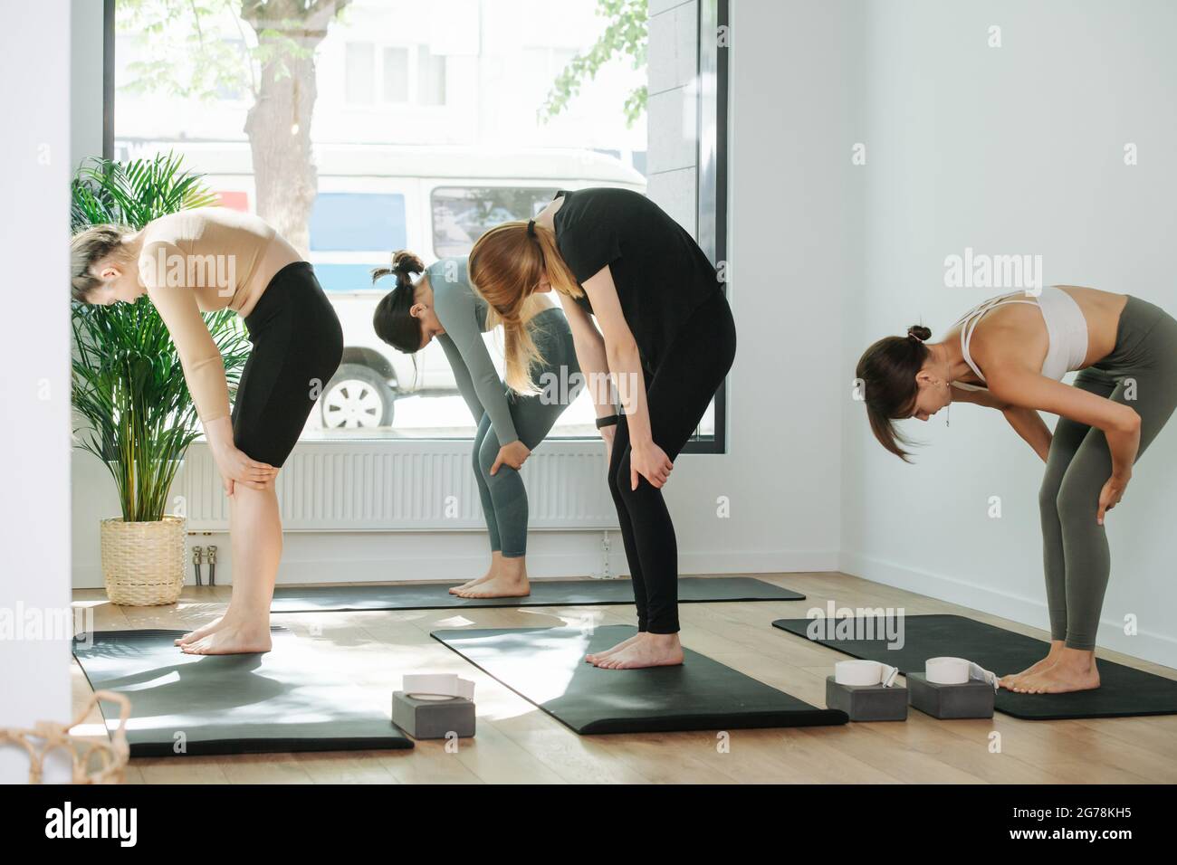 Groupe de femmes pratiquant le yoga à côté d'un instructeur, se pencher ...