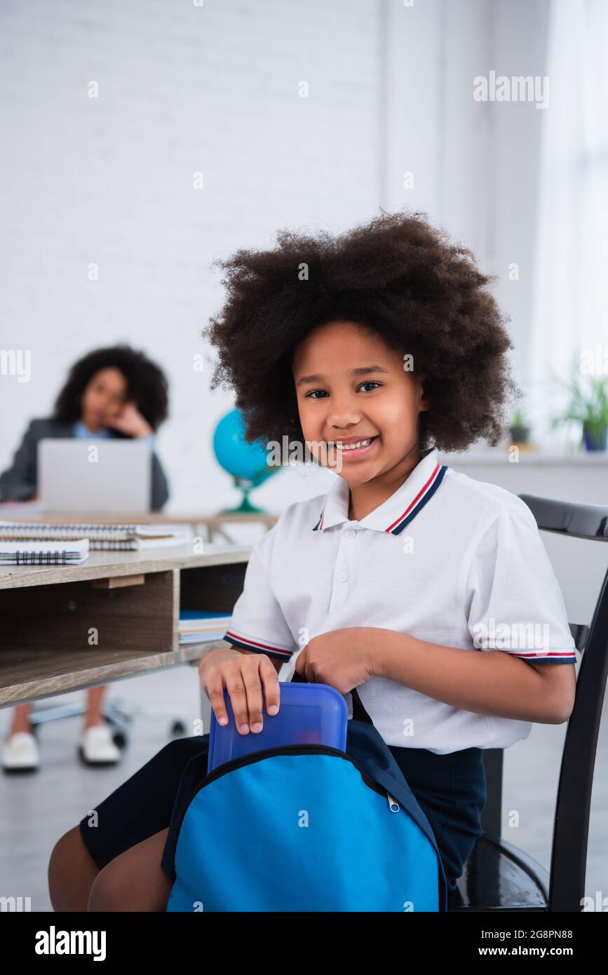Bon élève afro-américain qui prend sa boîte à lunch dans un sac à dos ...