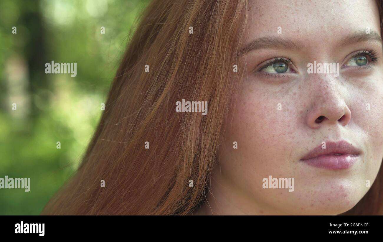 La fille aux cheveux rouges ouvre ses beaux yeux bleus. Gros plan sur ...