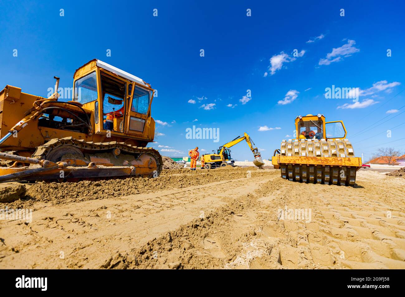 Le rouleau de route avec pointes et bulldozer compacter, nivelant le ...