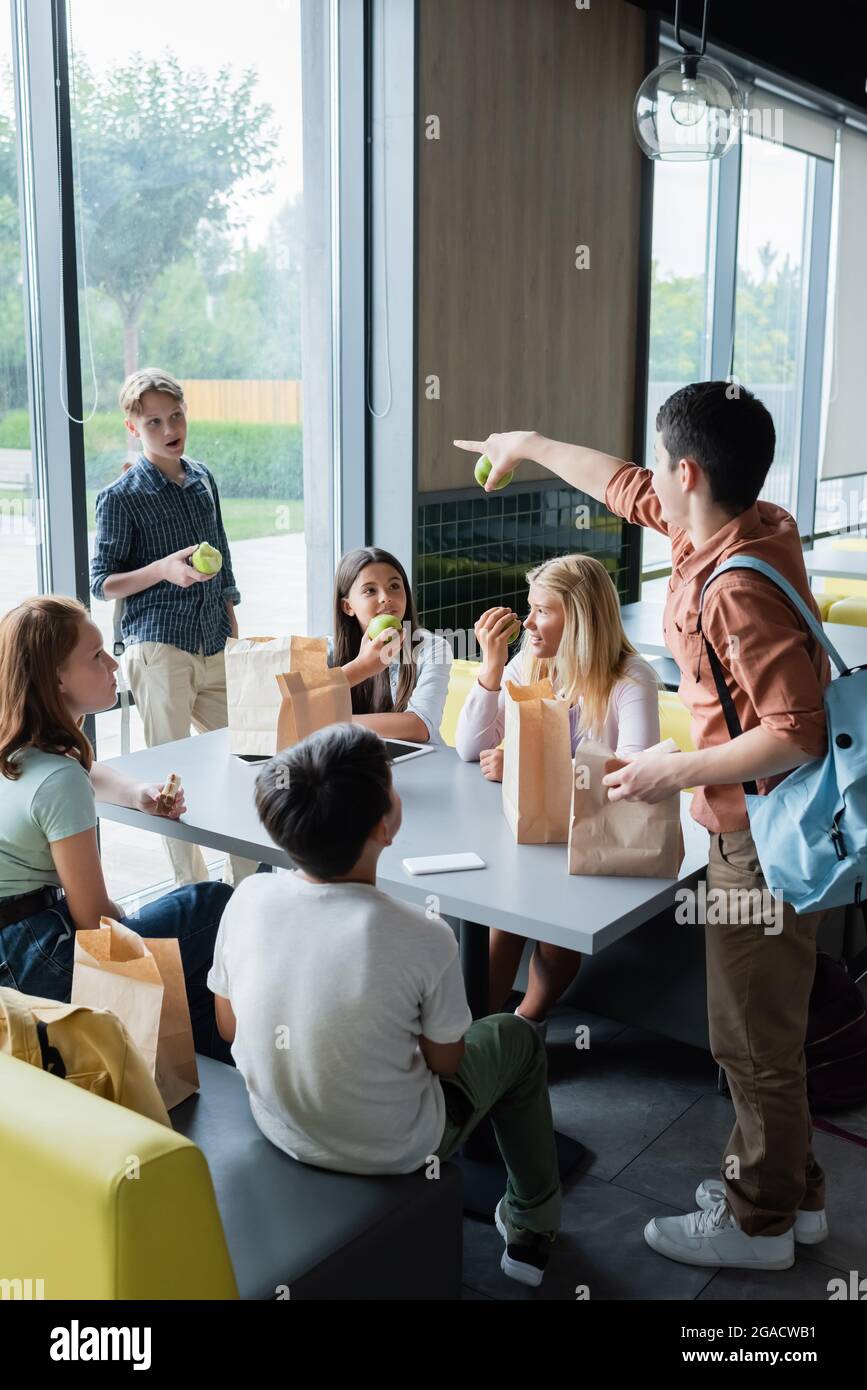 une adolescente pointant vers un camarade de classe près des élèves qui ...