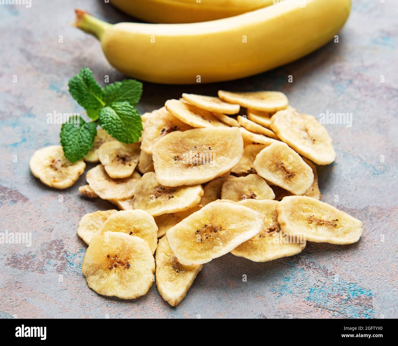 Tranches de banane confites séchées ou croustilles sur un béton gris ...
