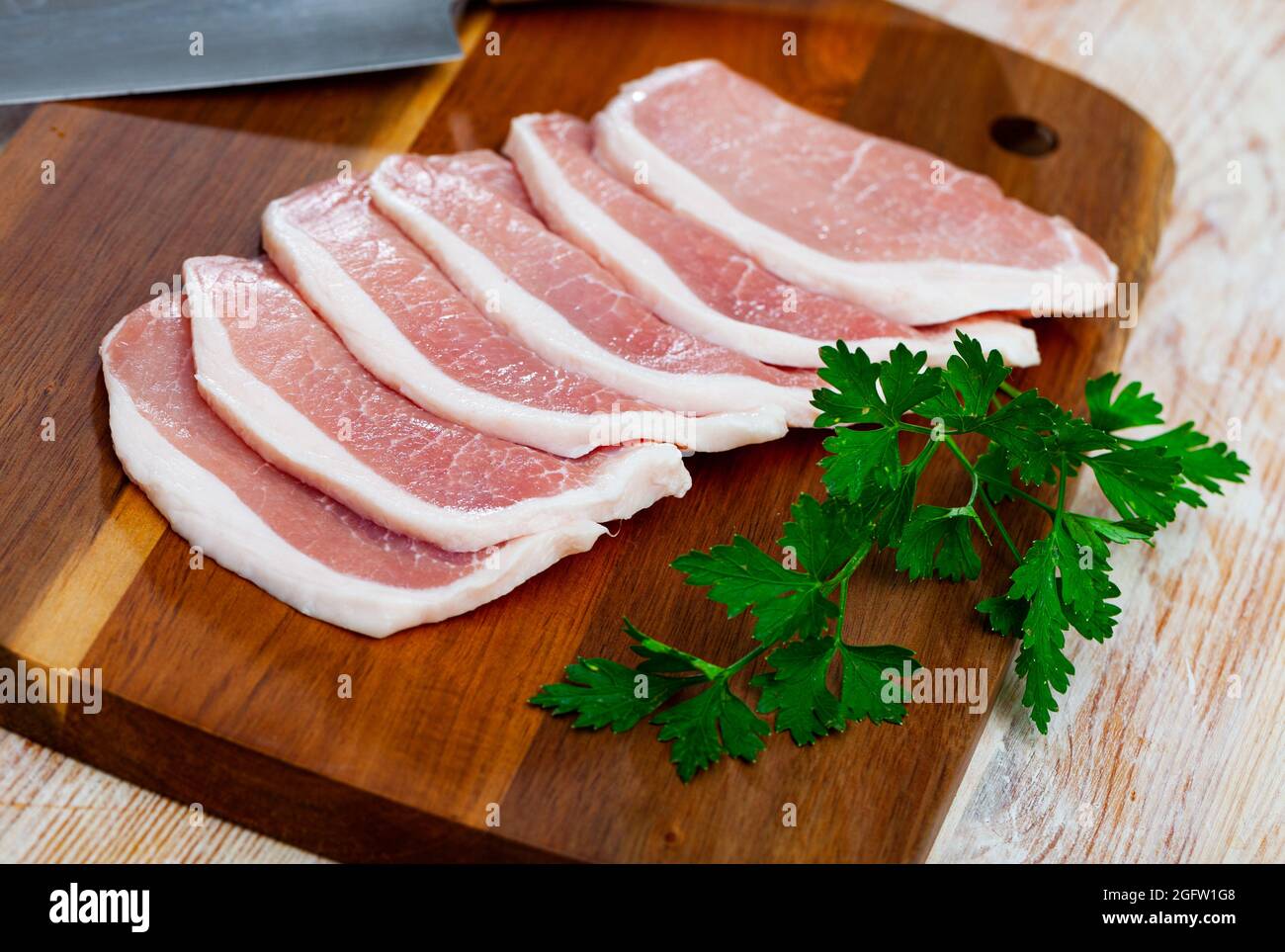 Côtelettes de porc crues sur une surface en bois avec du persil Photo ...