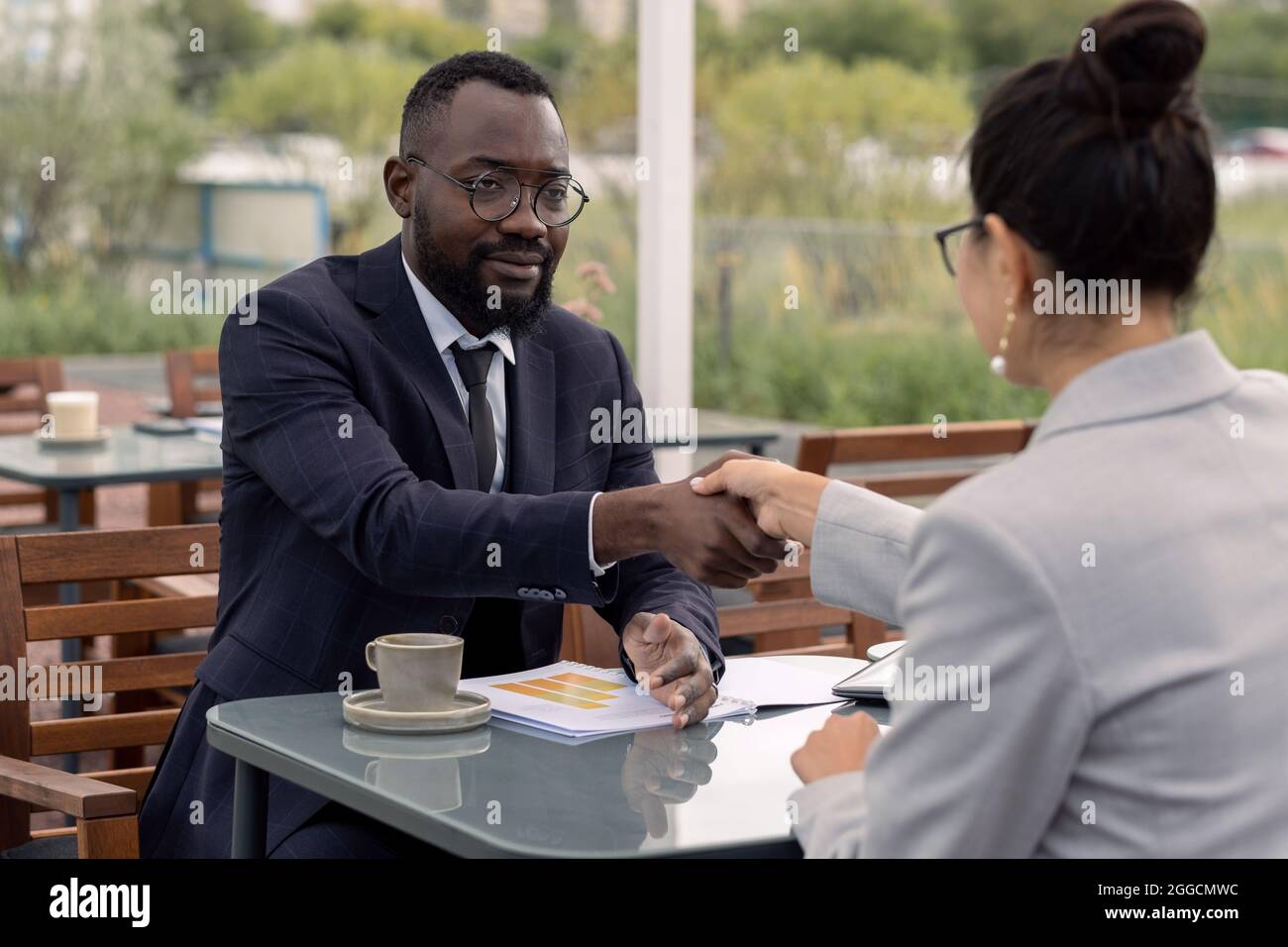 Un jeune courtier africain en costume élégant secouant la main de la ...