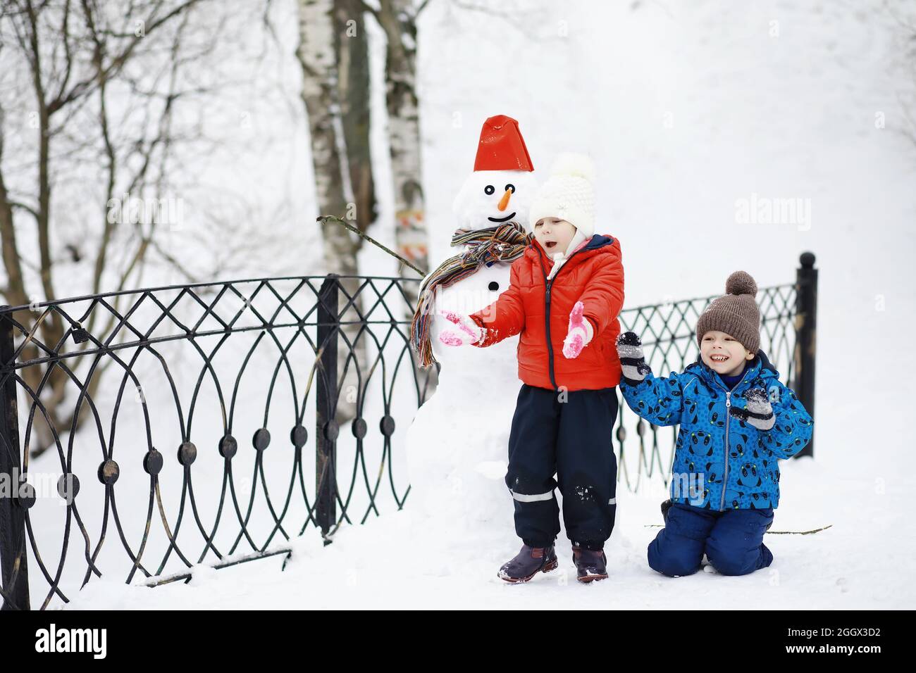 Enfants dans le parc en hiver. Les enfants jouent avec la neige sur l ...