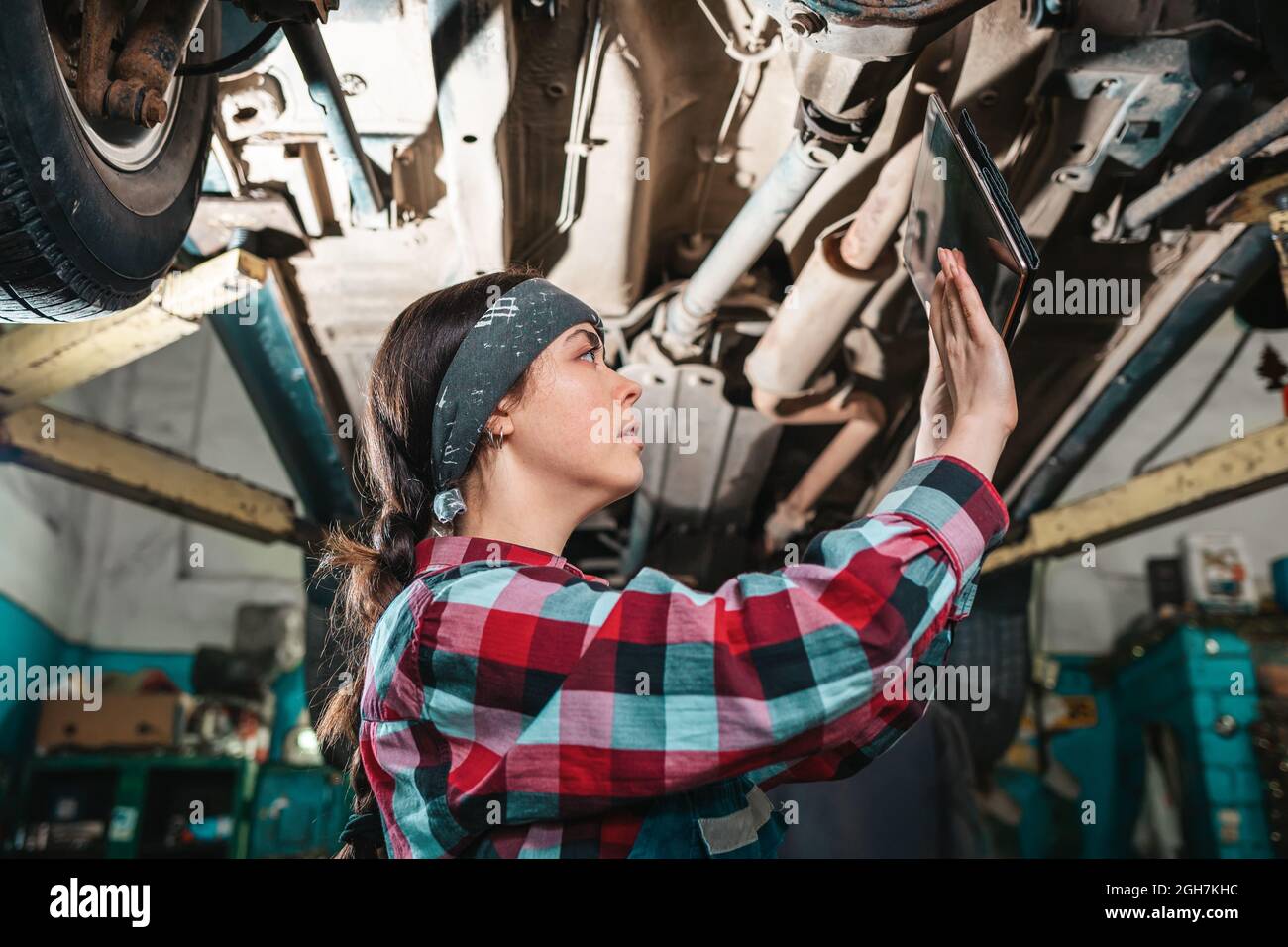 Portrait d'une jeune femme mécanicien en uniforme qui utilise une tablette pour diagnostiquer ...
