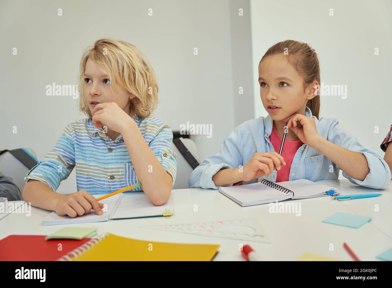 Petit écolier attentif et écolière étudiant et listenen à l'enseignant ...
