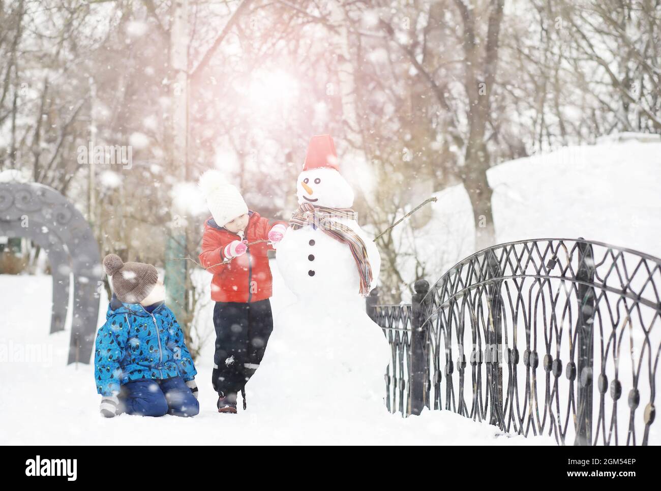 Enfants dans le parc en hiver. Les enfants jouent avec la neige sur l ...