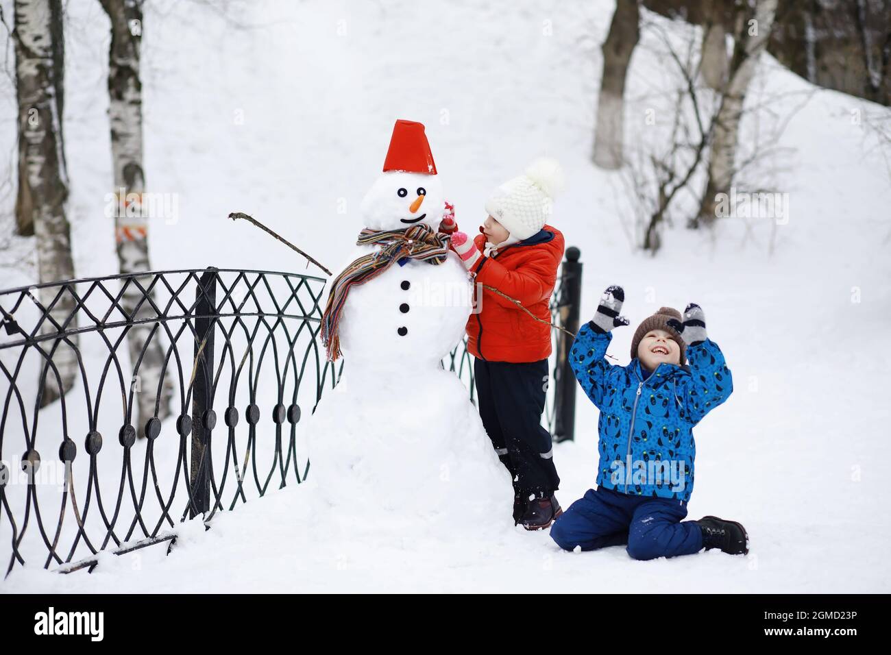 Enfants dans le parc en hiver. Les enfants jouent avec la neige sur l ...