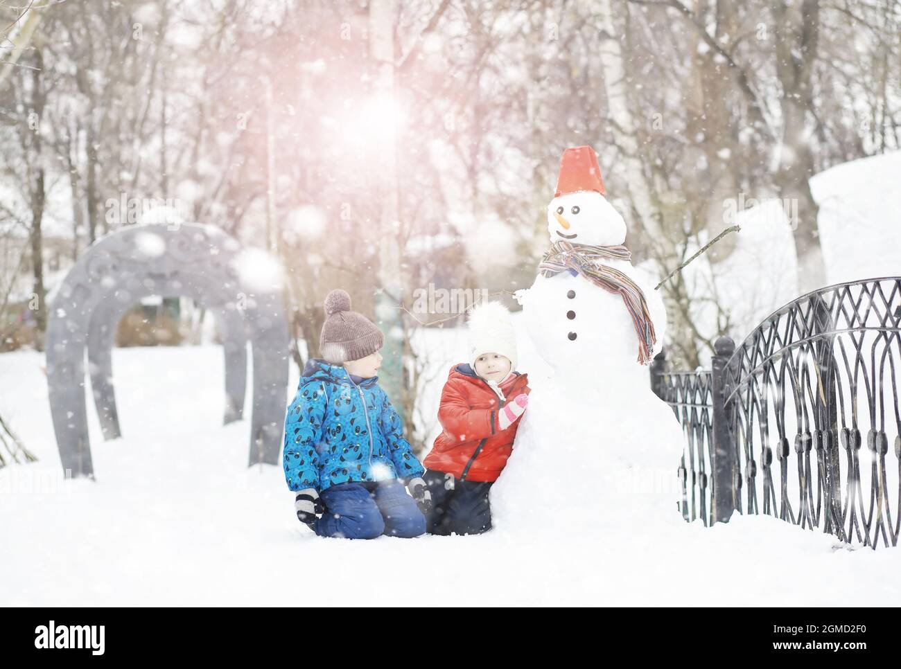 Enfants dans le parc en hiver. Les enfants jouent avec la neige sur l ...