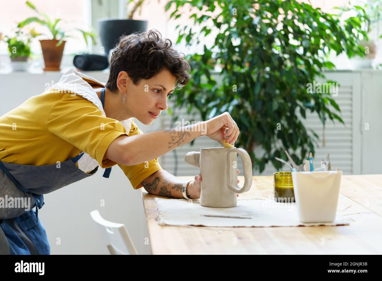 Jeune fille artisan occupé avec la carafe à modeler de l'argile brute ...