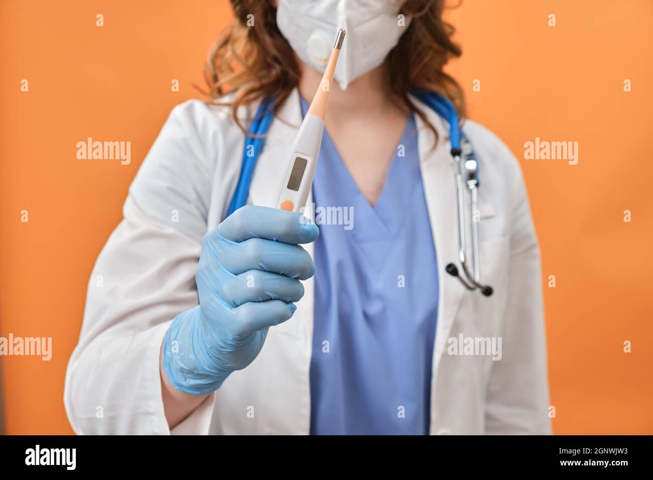 Une femme médecin tient un thermomètre numérique électronique dans sa ...